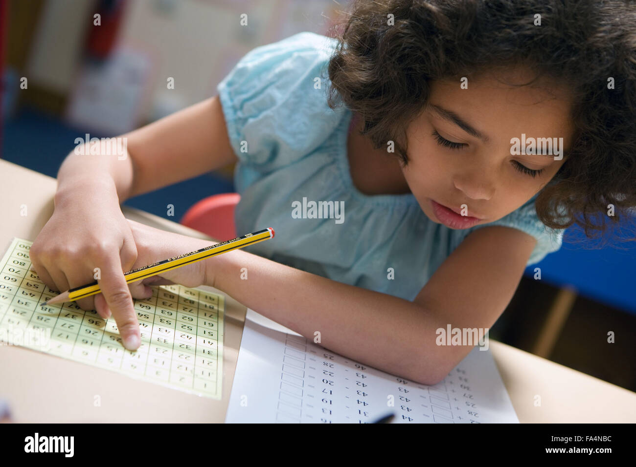 Young girl sitting at desk in classroom working on maths problem Stock ...