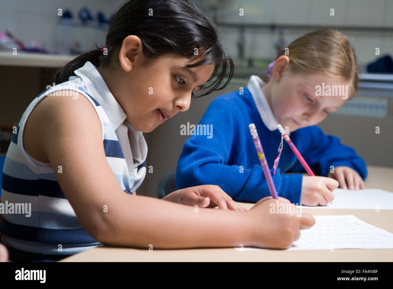 Two girls sitting at desk in classroom working on maths problems Stock ...