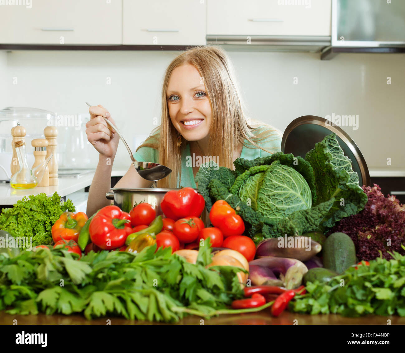 happy long-haired woman cooking with heap of raw vegetables in home ...