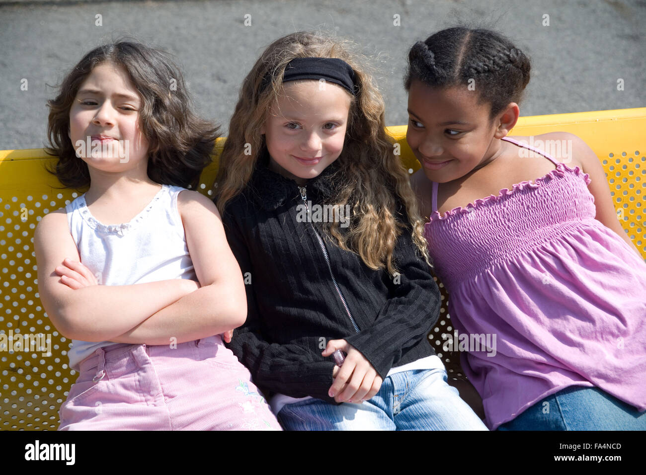 Group of girls sitting together on bench in school playground smiling ...