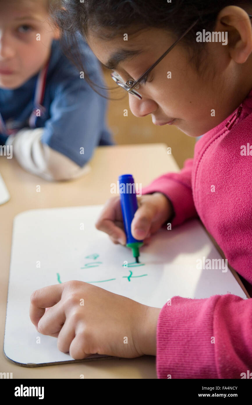 Girl sitting at desk in classroom practising writing skills Stock Photo ...