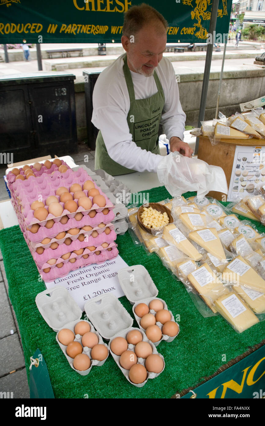 Stallholder serving fresh local produce on a stall at an outdoor Farmer ...