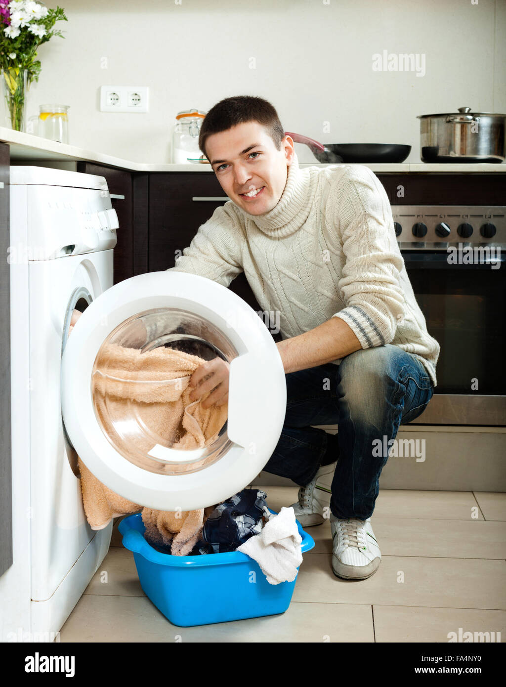 Cheerful guy doing laundry with washing machine at home Stock Photo - Alamy