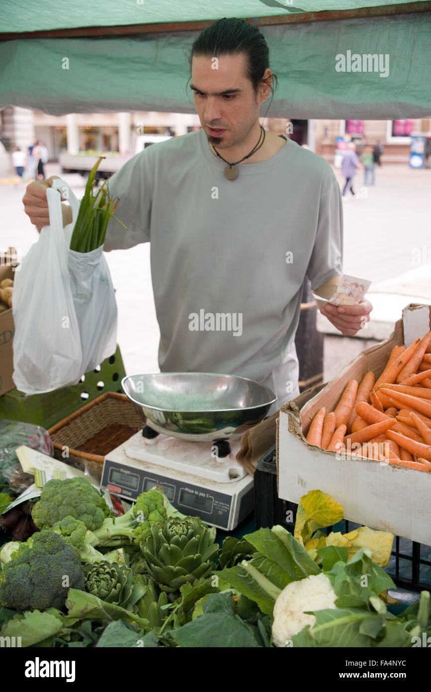 Stallholder serving fresh local produce on a stall at an outdoor Farmer ...