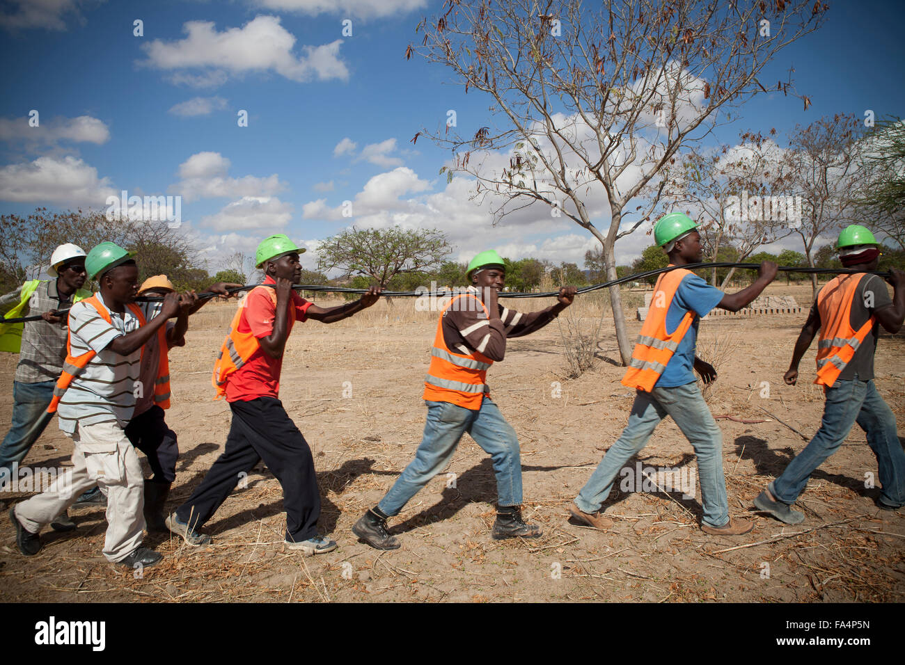 Workers string new power cables in a rural village near Dodoma ...