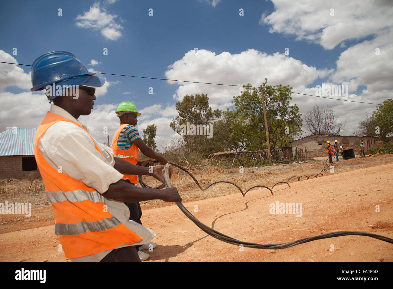 Workers string new power cables in a rural village near Dodoma ...