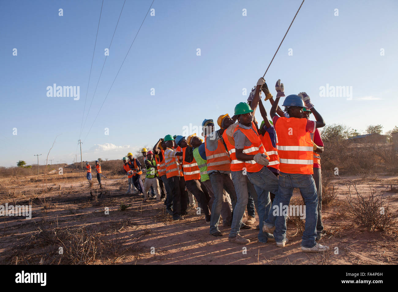 Workers string new power cables in a rural village near Dodoma ...