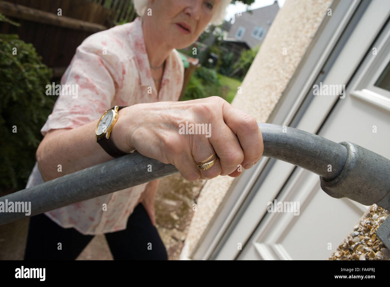 Woman, using grab handrails to help her up the steps outside her front ...