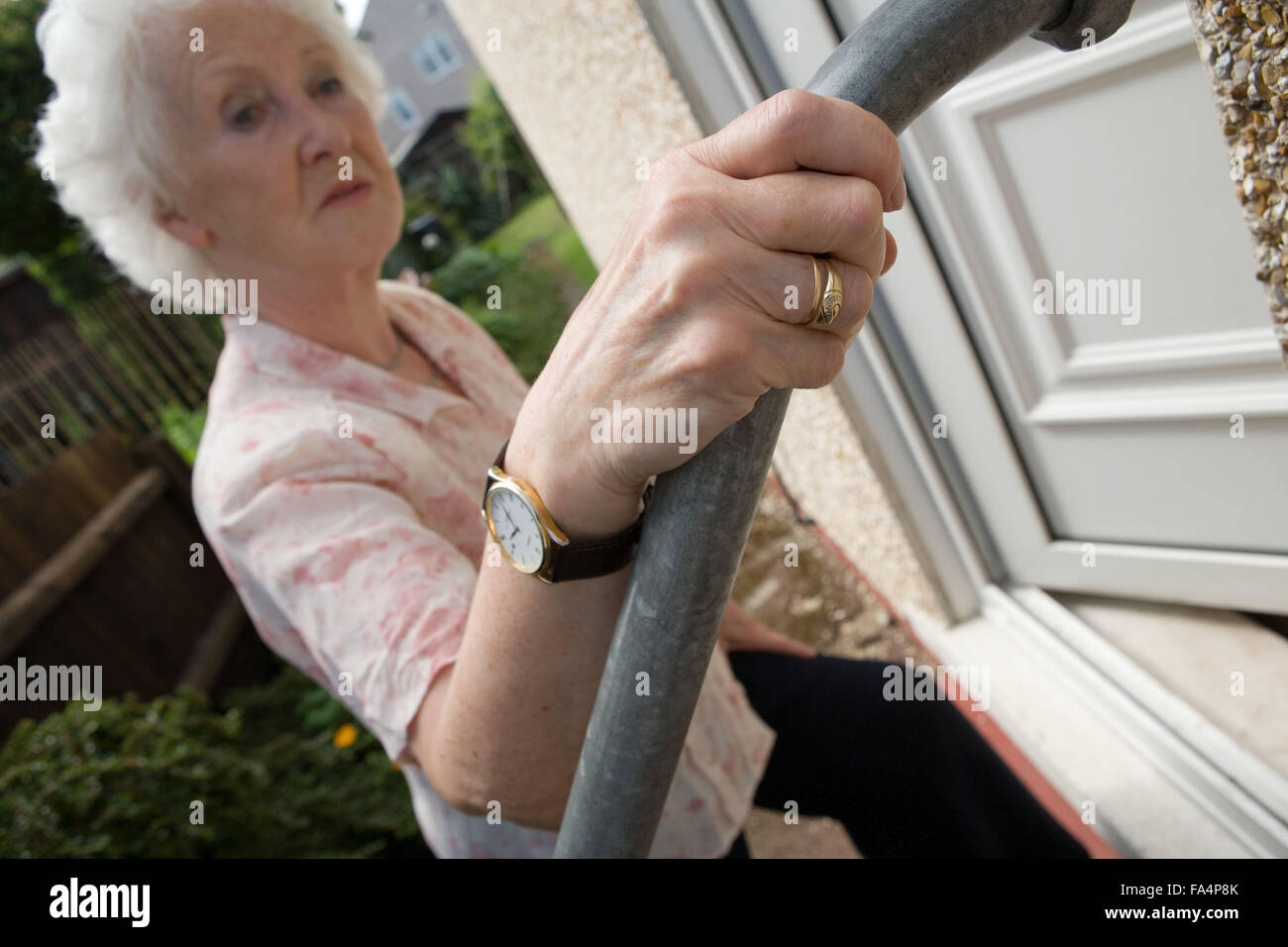 Woman using grab handrails to help her up the steps outside her front ...
