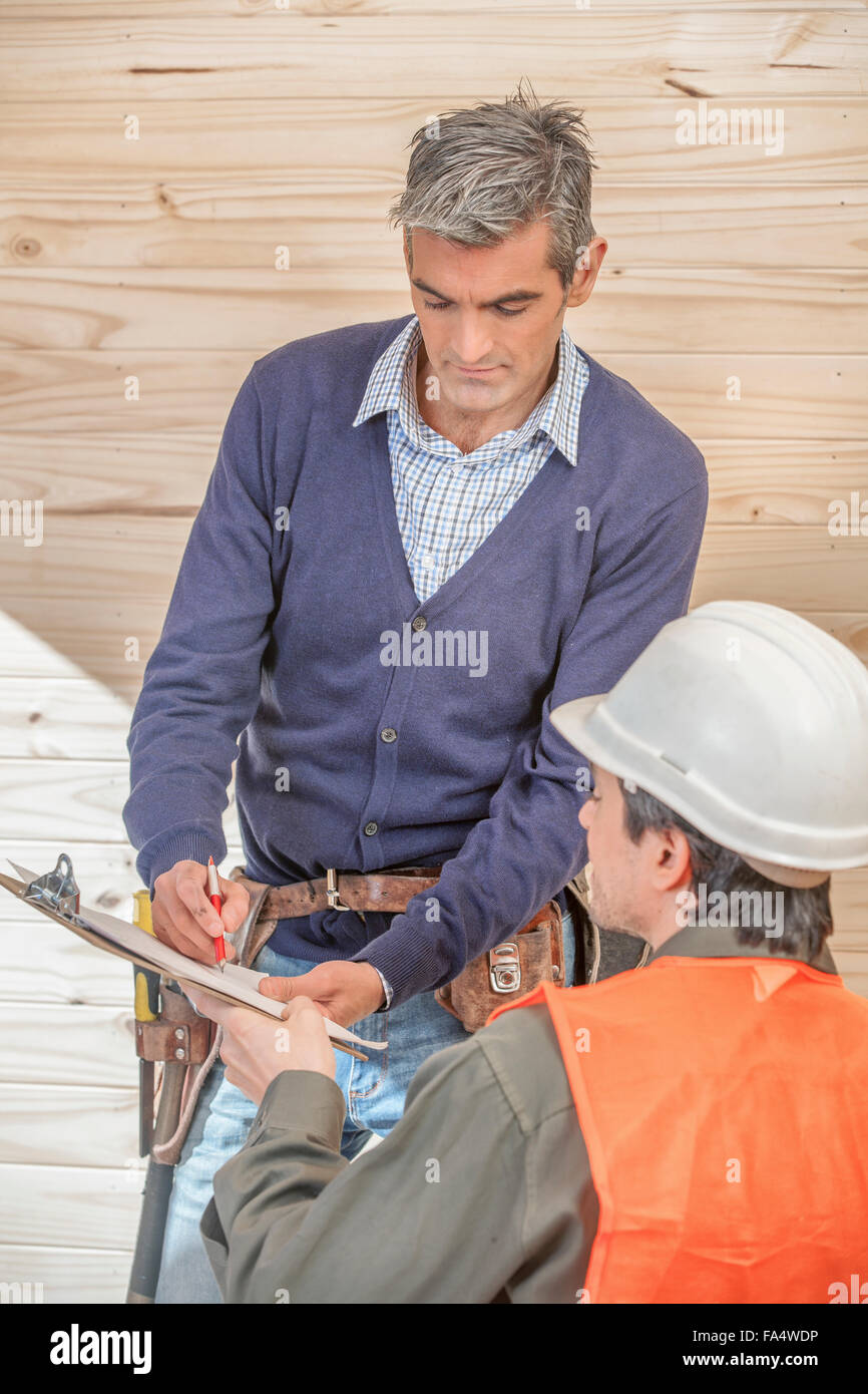 Builder On Building Site Looking At Plans With Apprentices Stock Photo ...
