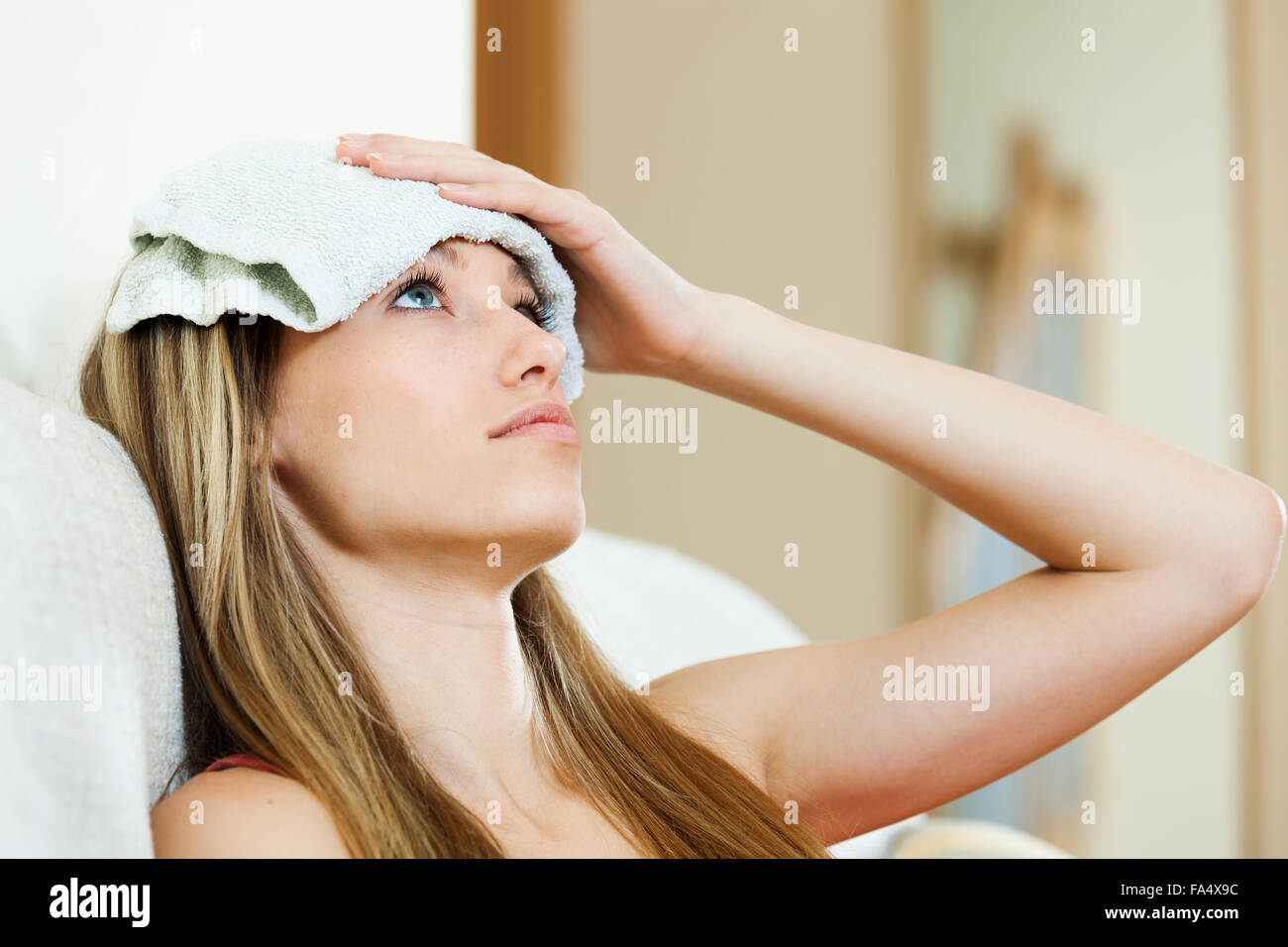 Sad girl with wet towel on forehead Stock Photo - Alamy