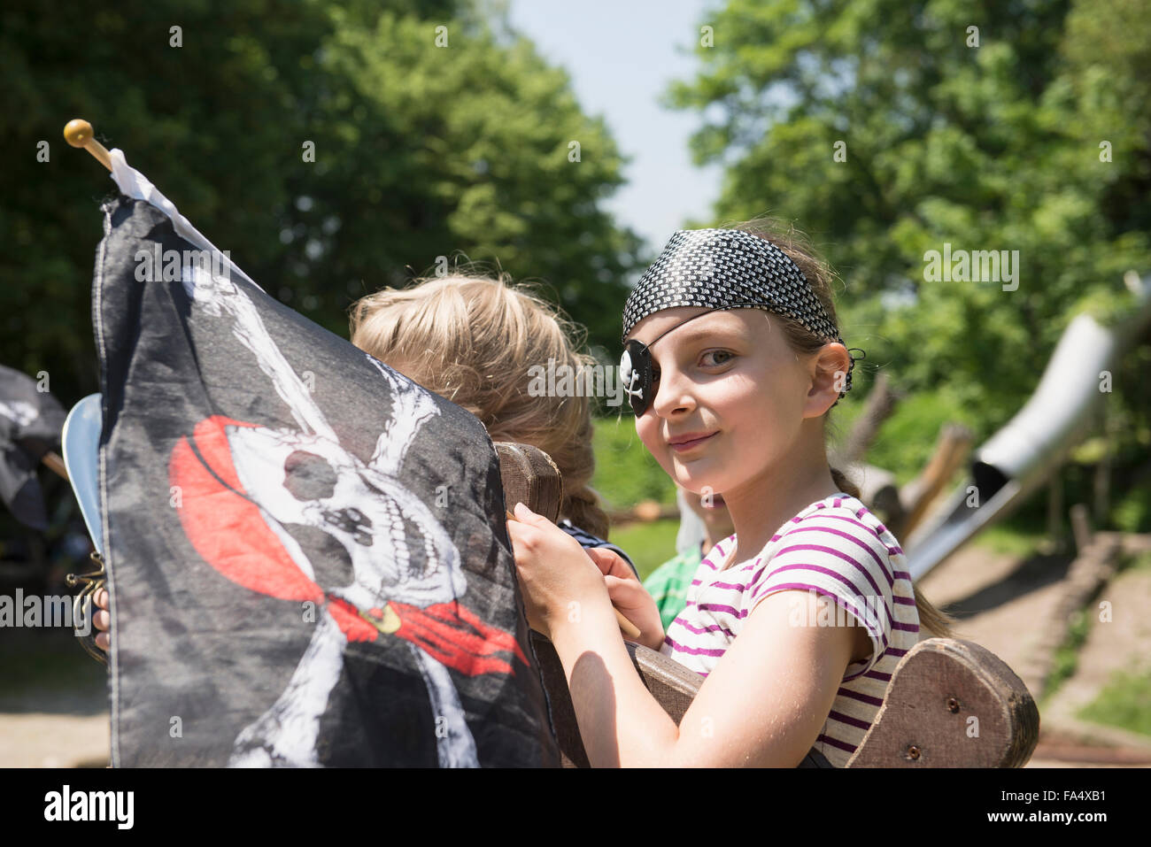 Portrait of a girl dressed up as a pirate holding pirate flag in ...