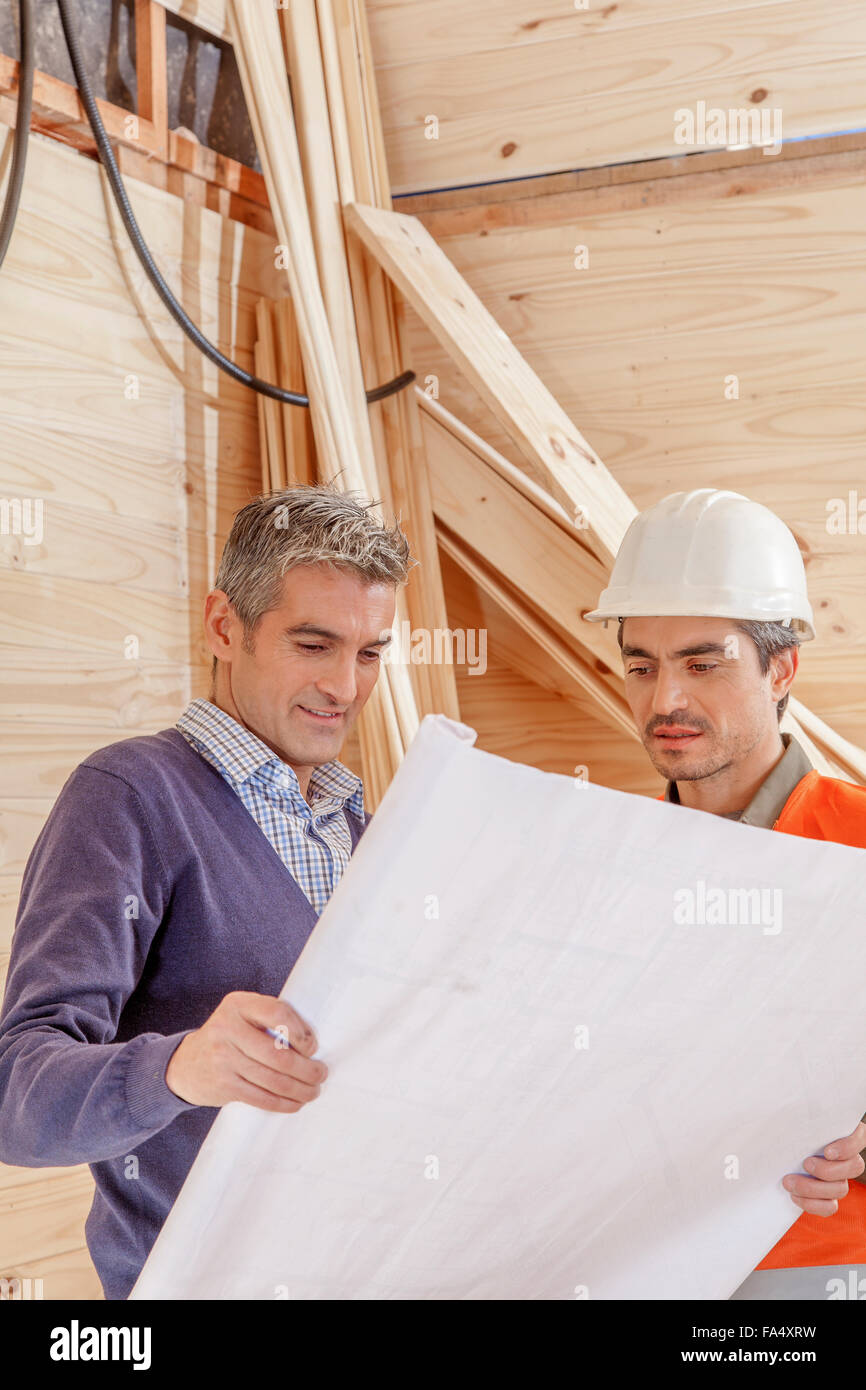 Builder On Building Site Looking At Plans With Apprentices Stock Photo ...