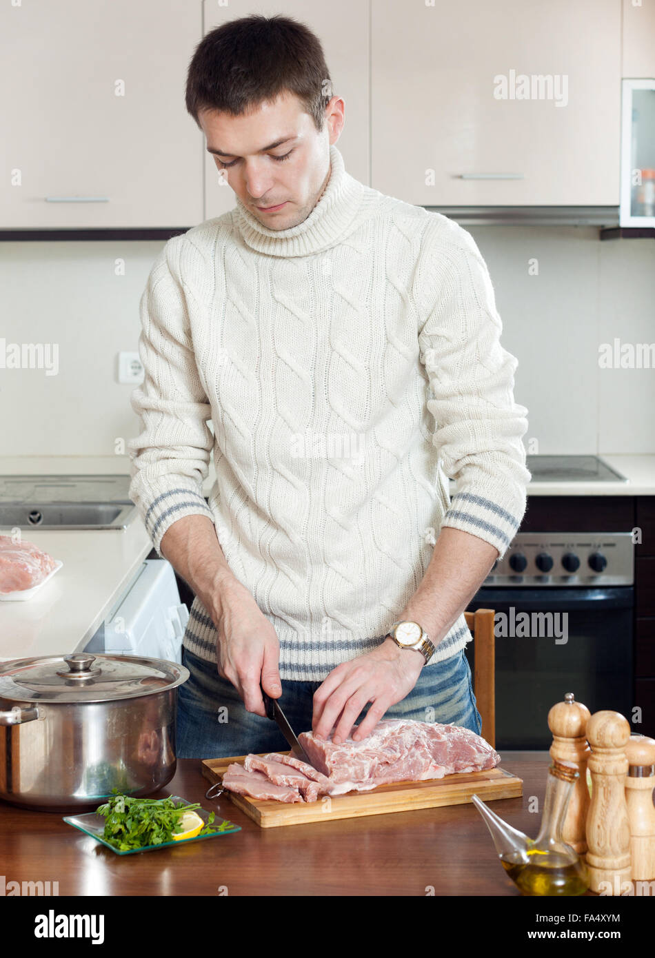 Handsome happy guy cutting meat at kitchen Stock Photo - Alamy