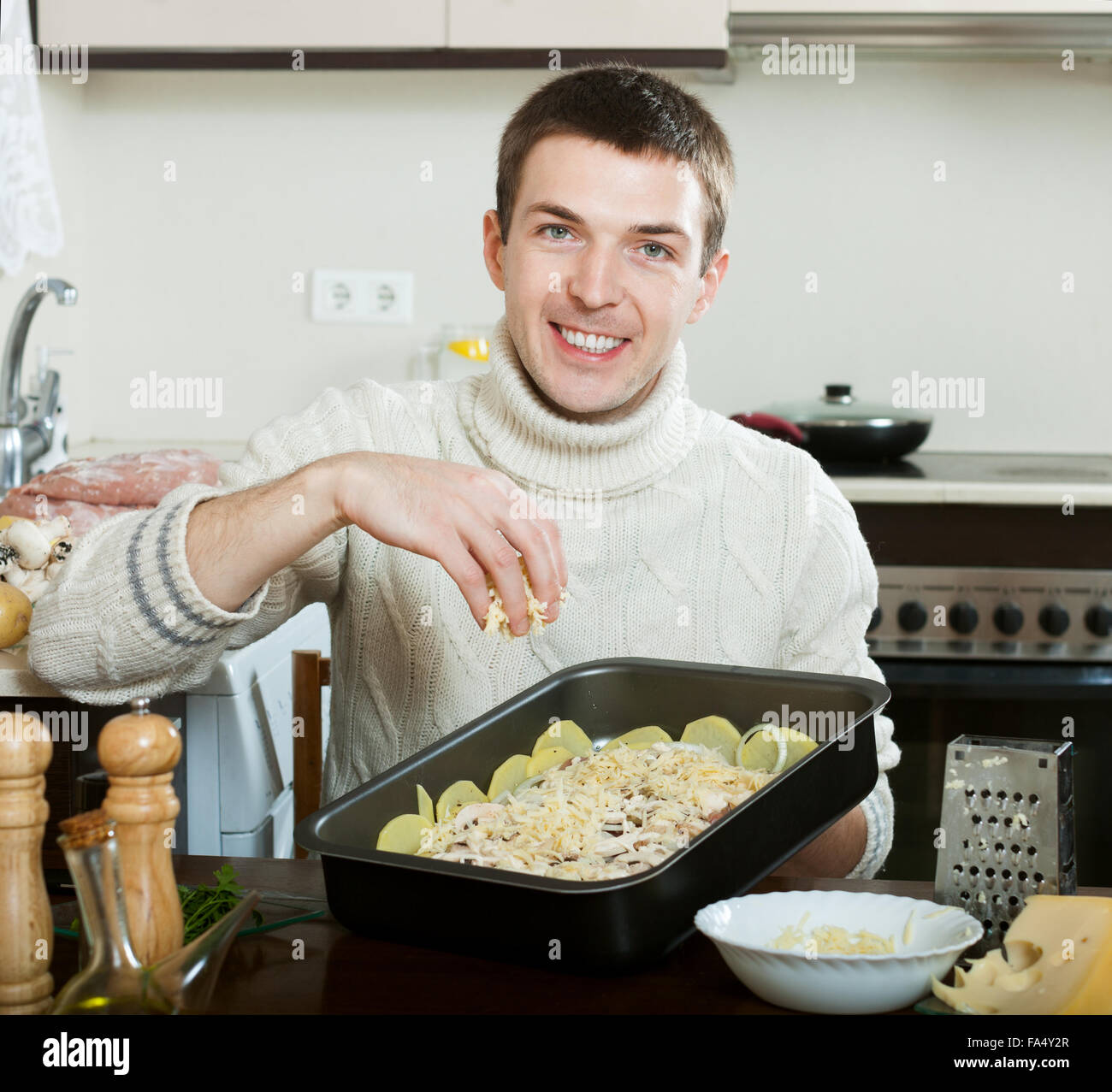 Guy cooking french-style veal. Adding grating cheese in roasting pan ...