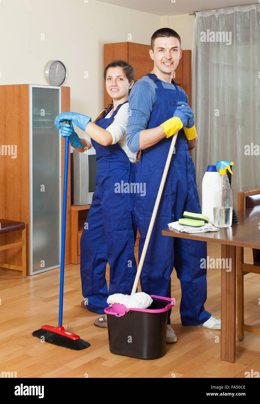 Smiling cleaners team working at living room Stock Photo - Alamy