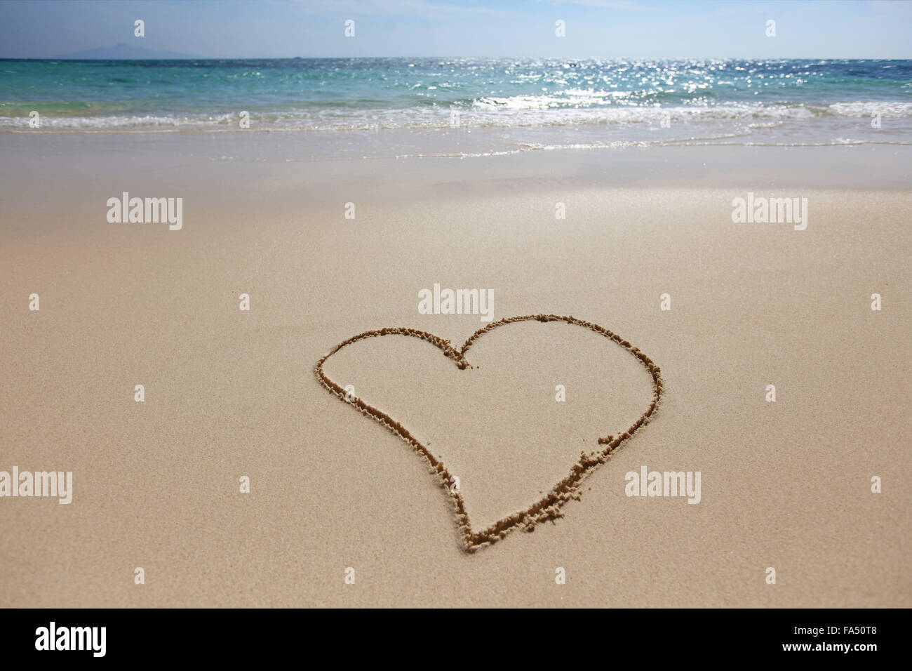 Heart drawing in the sand on the beach, blue waves on background Stock ...