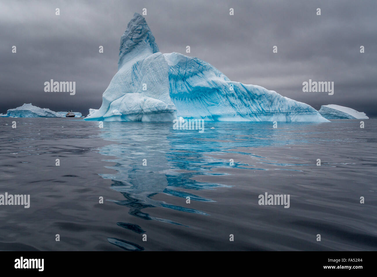 Huge iceberg with a cruise ship for size comparison, set off vibrantly ...