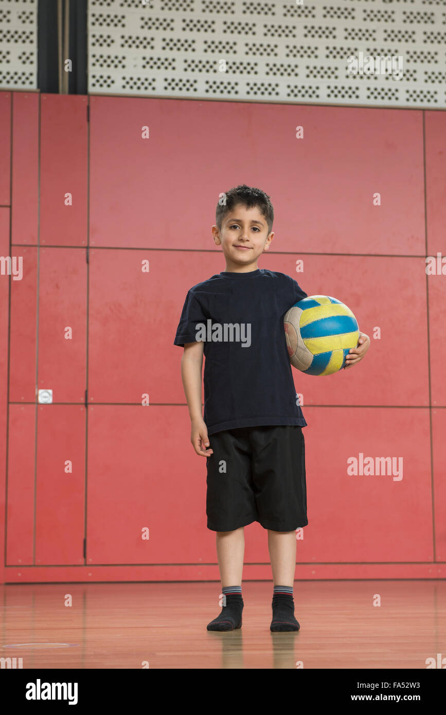 Portrait of a schoolboy holding a ball in sports hall of school, Munich ...