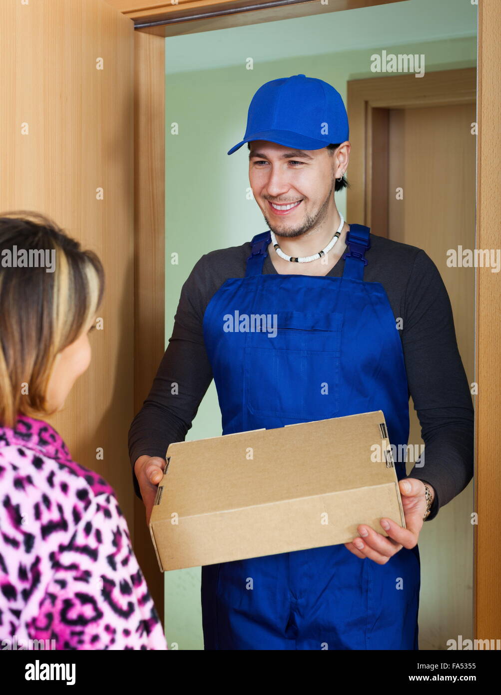 Joyful postman in uniform delivered box to woman at home Stock Photo ...