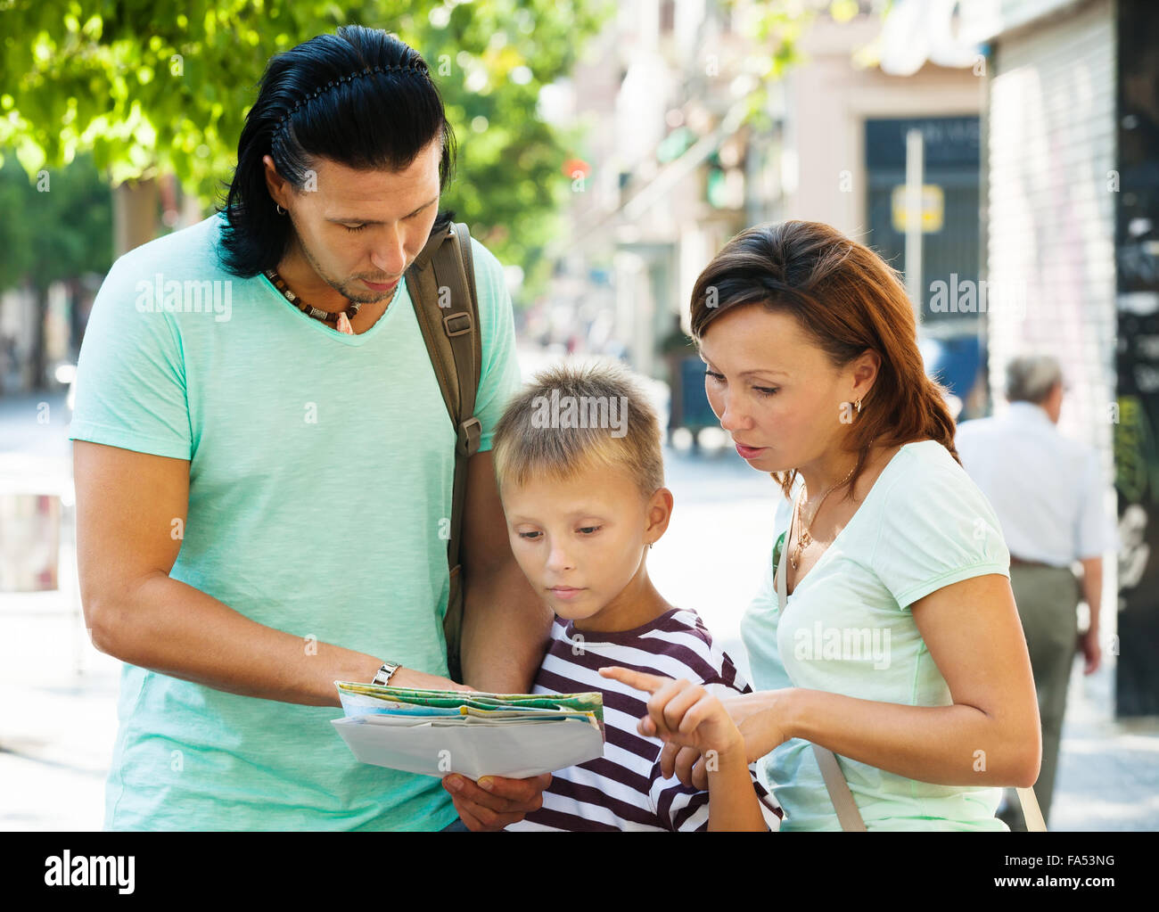 Traveling family looking at the map in city street Stock Photo - Alamy