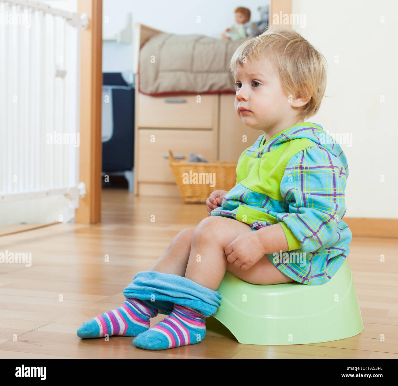 Baby sitting on green potty in home interior Stock Photo - Alamy