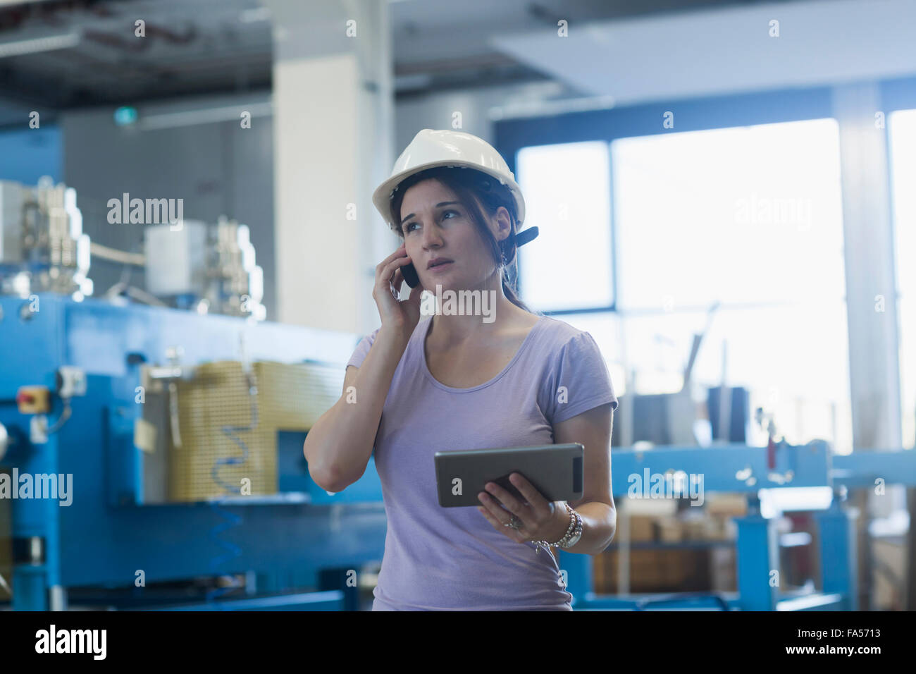 Female engineer using a digital tablet and mobile phone in an ...