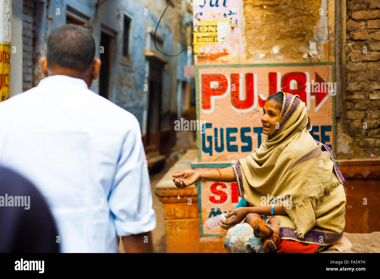 A poor female beggar sitting with baby extending her hand begging for ...