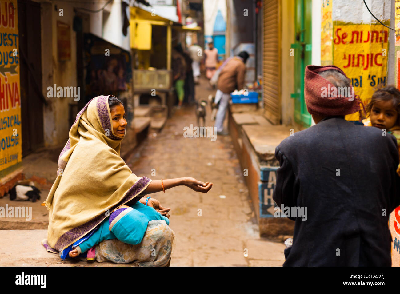 Poor woman sitting in dirty back alley holding baby begging for money ...