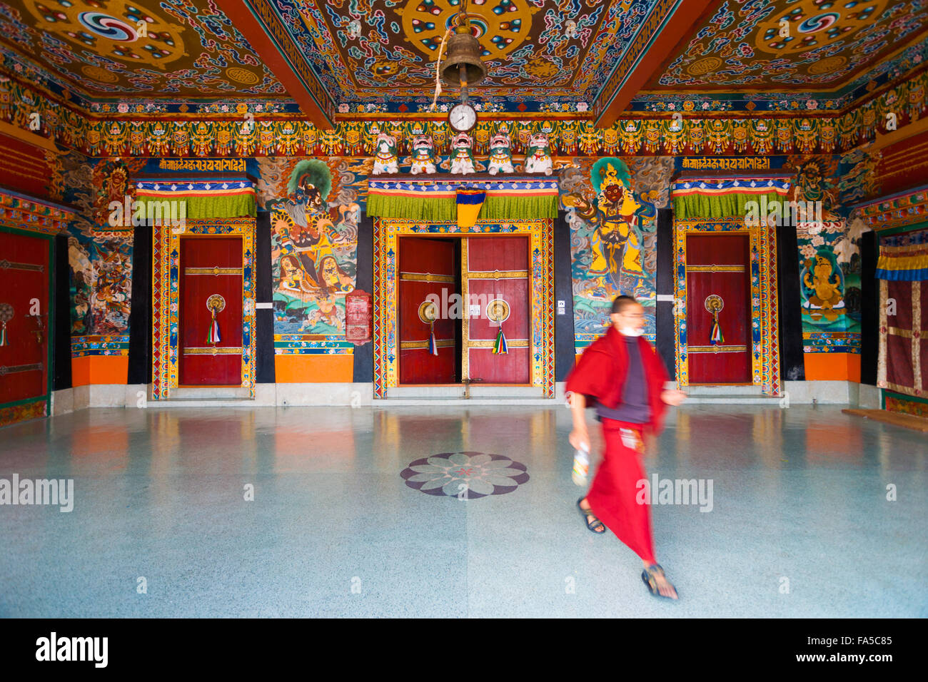 A monk walks out of the colorful entrance of the Rumtek Monastery, a ...
