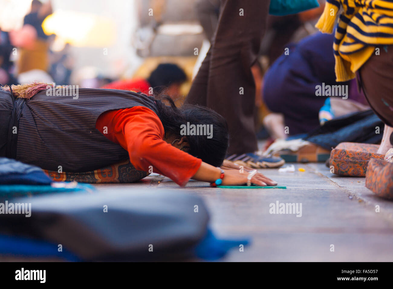 Tibetan woman prostrating, lying flat on stomach, head to ground, arms ...