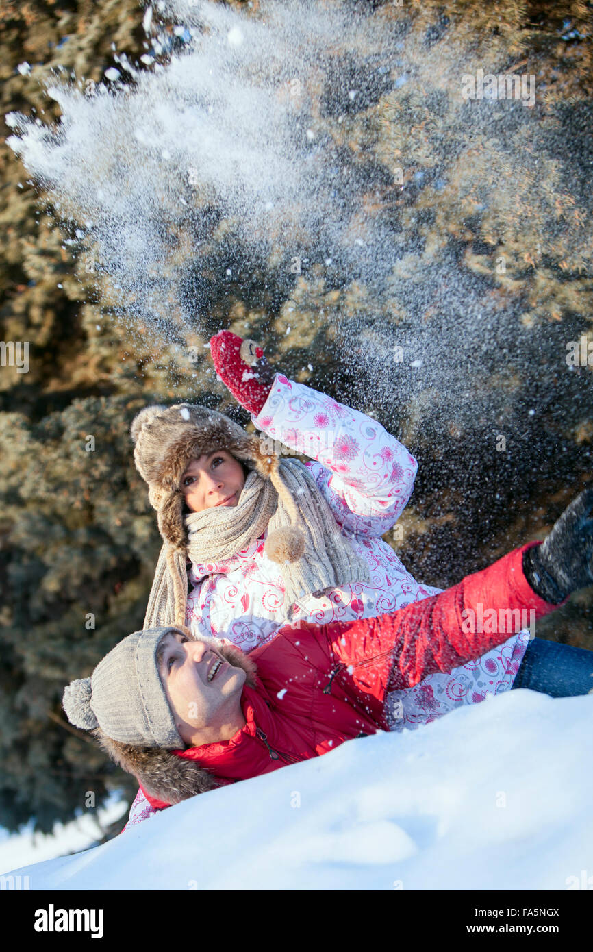 In winter, walking man and woman lie on the snow throw snow up Stock ...