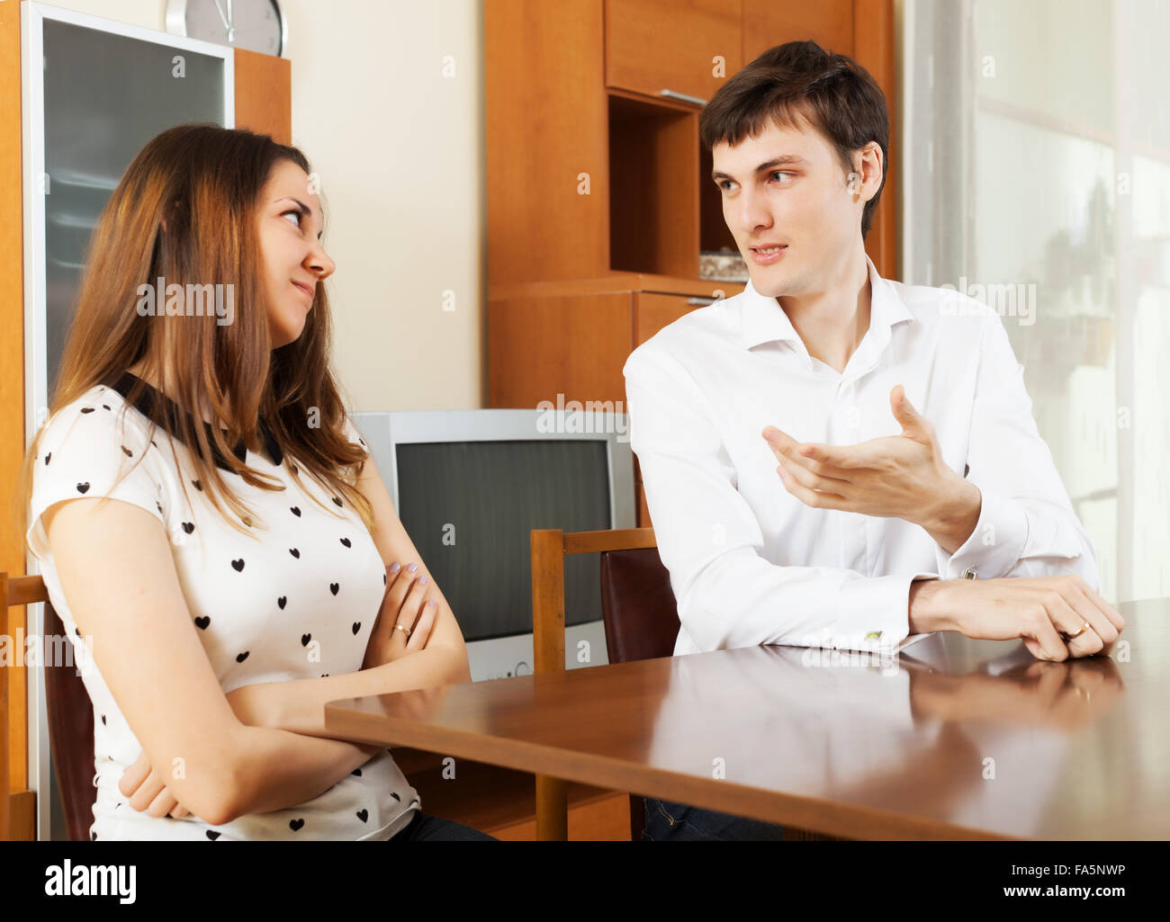 Casual young couple having serious talking at table in home. Focus on ...