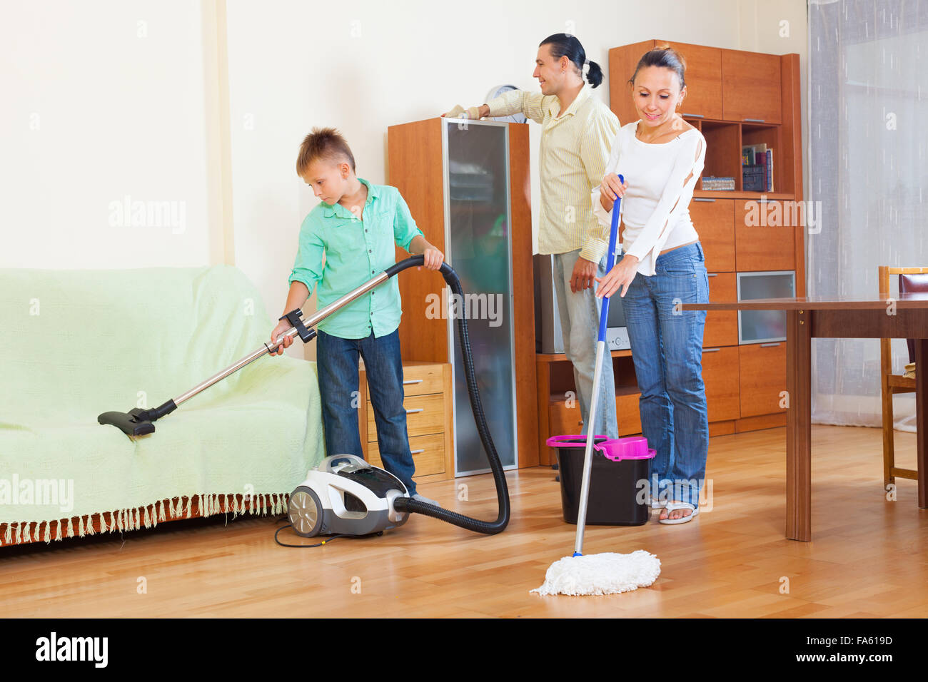family of three doing housework in home Stock Photo - Alamy