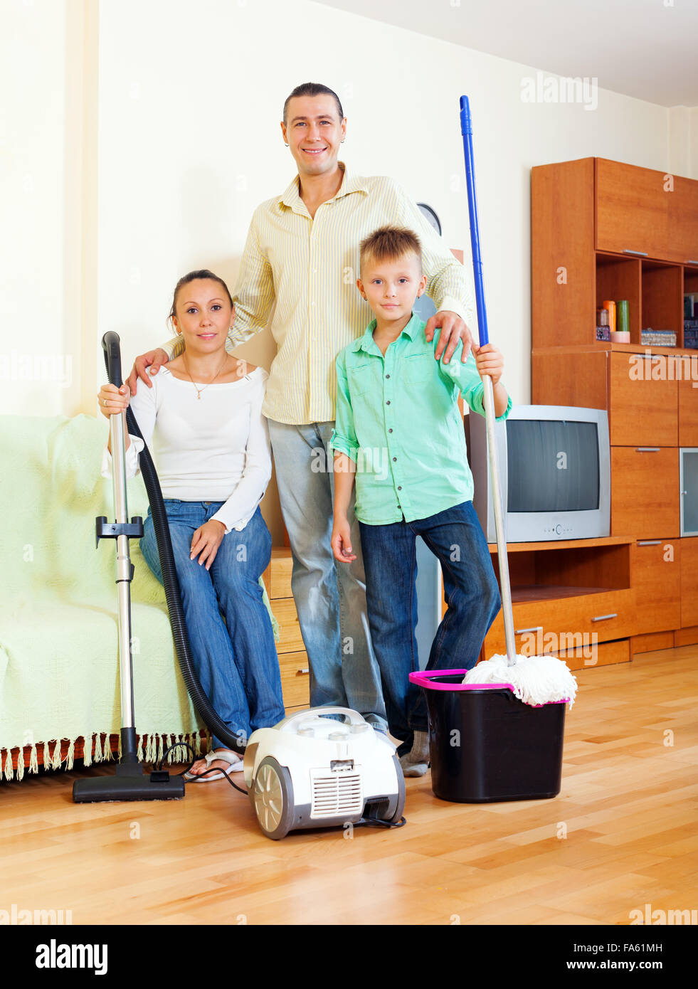Portrait of happy family of three with cleaning equipment in home Stock ...