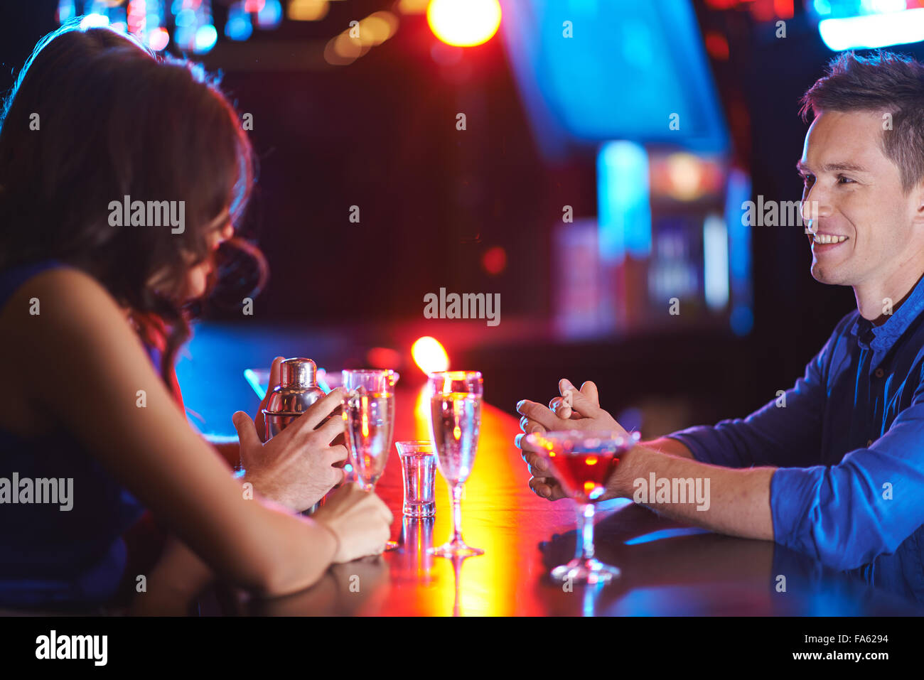 Happy young man talking to girl while having drink in night club Stock ...