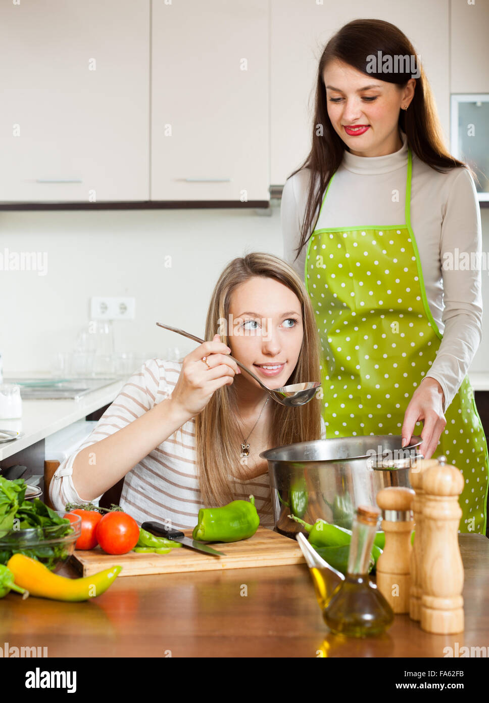 girls cooking together at domestic kitchen. Focus on blonde Stock Photo ...