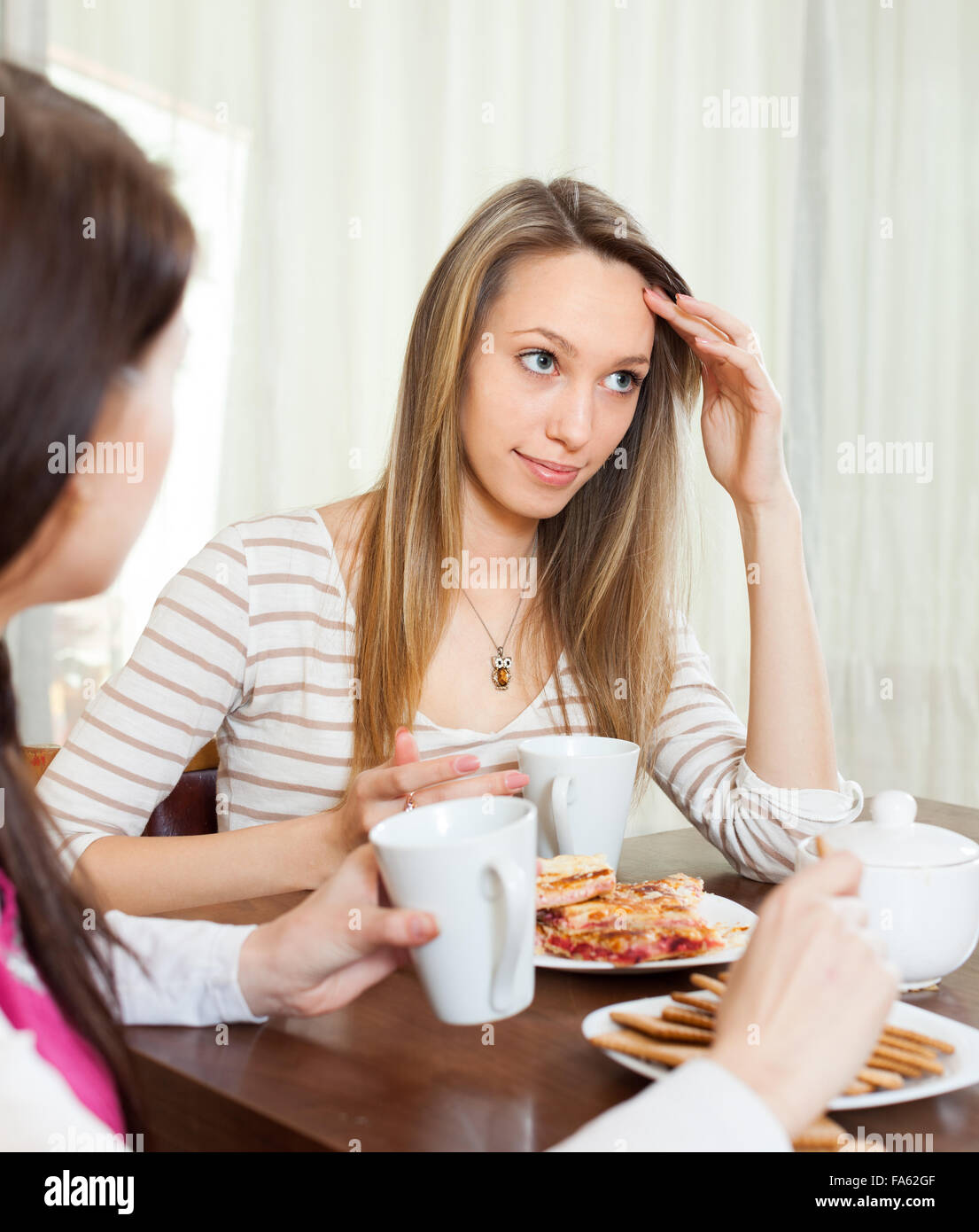Two serious women speakong over tea table in kitchen Stock Photo - Alamy