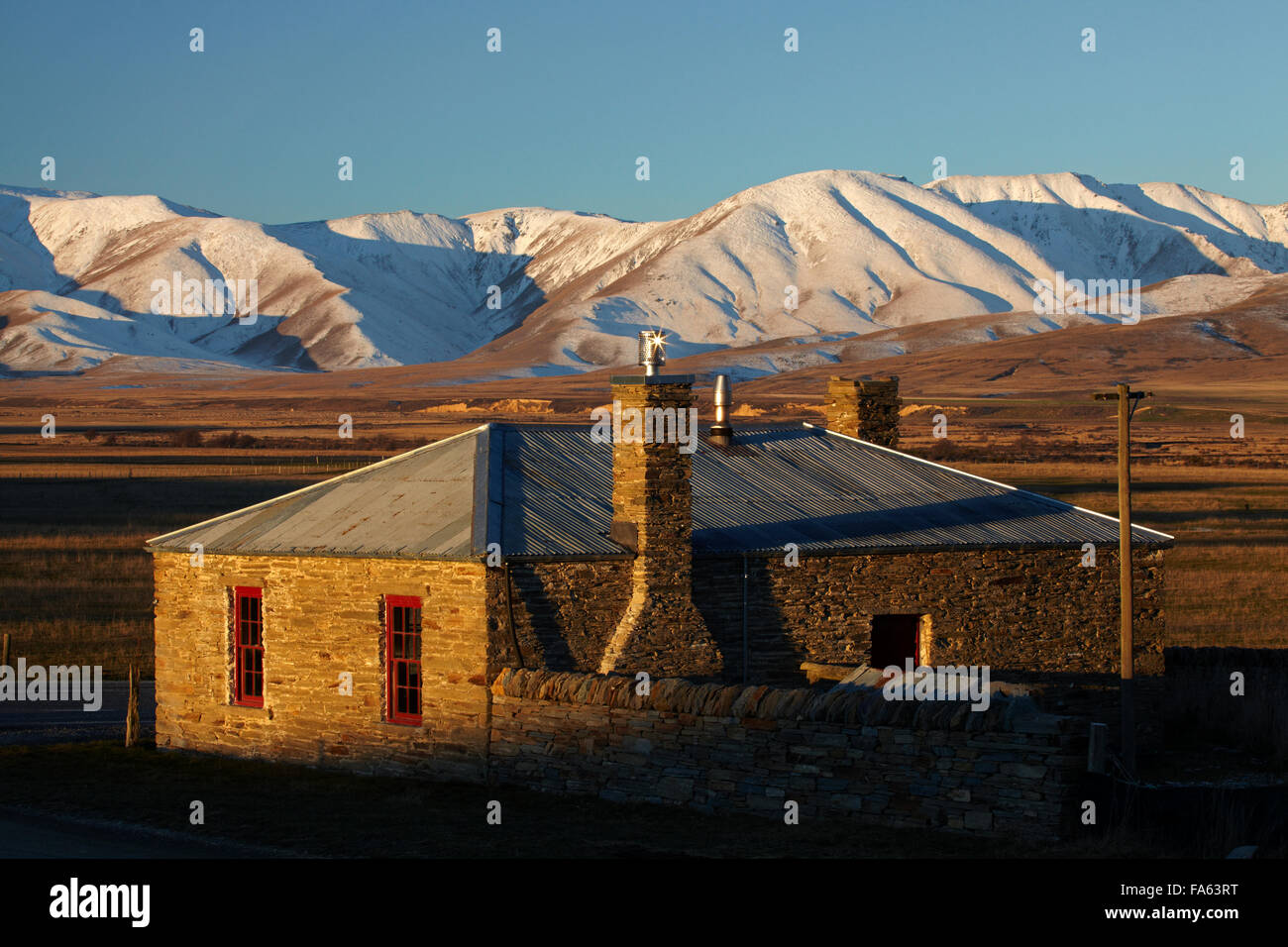 Historic stone cottage and Ida Range in winter, Hills Creek, Maniototo ...