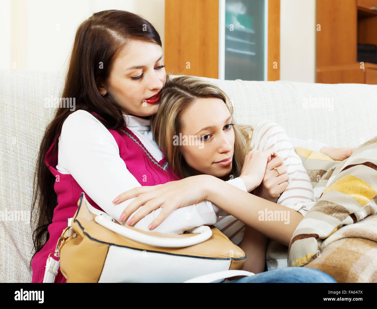 Young woman comforting crying friend at sofa in home Stock Photo - Alamy