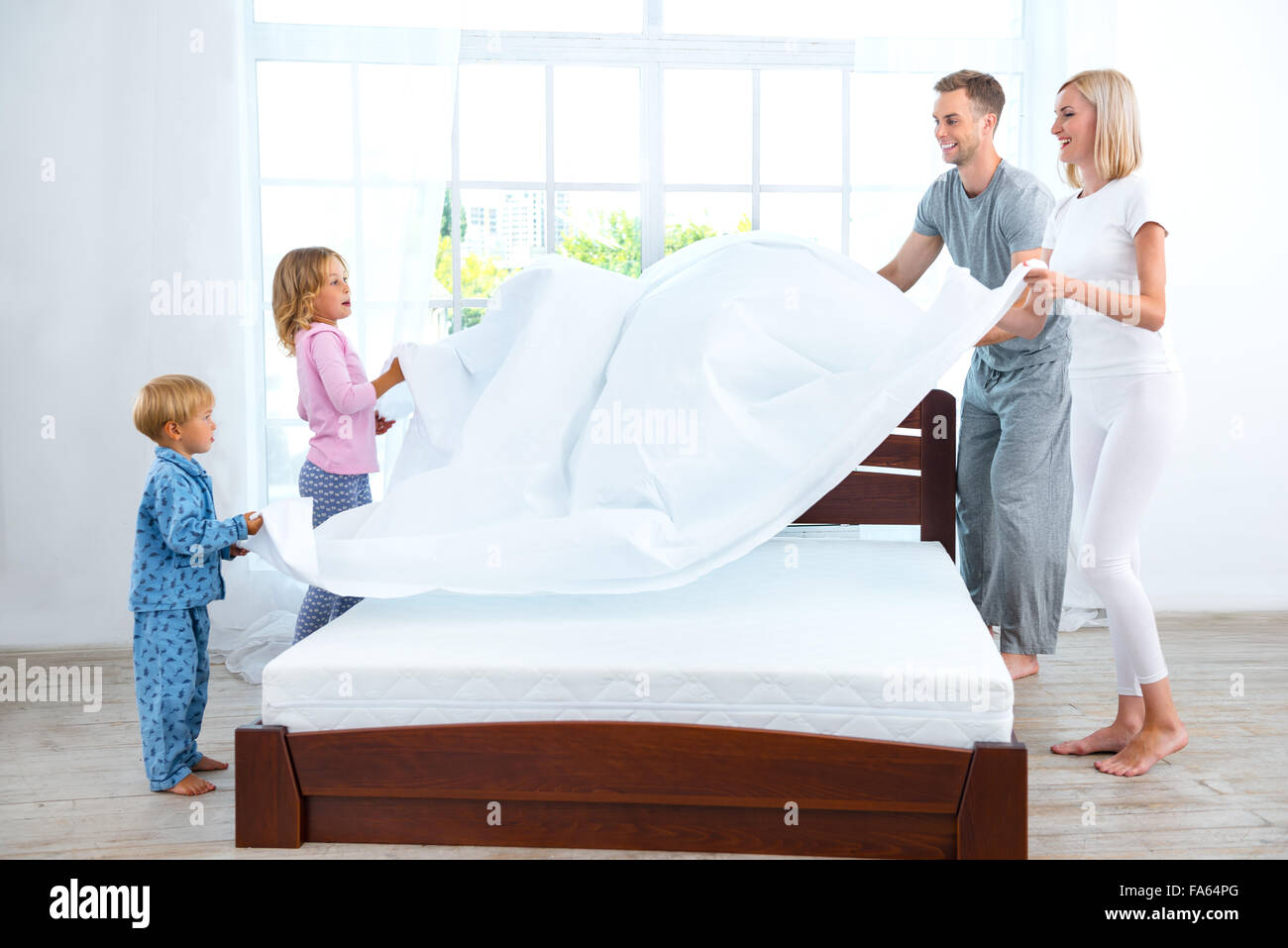 Young nice family making bed Stock Photo - Alamy