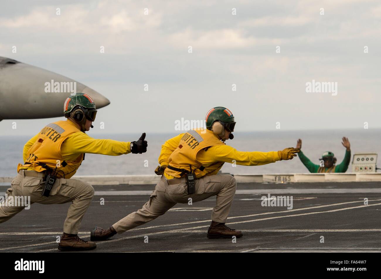 US Navy sailors give the go signal to a fighter aircraft aboard the ...