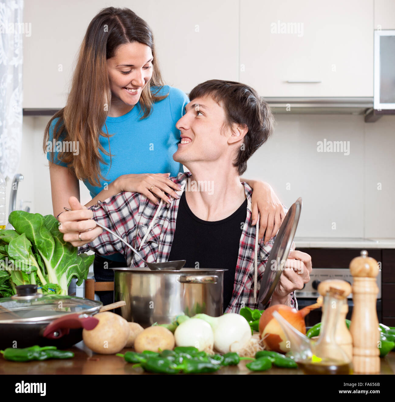 man suggests to try the cooked food to the girl in house kitchen Stock ...