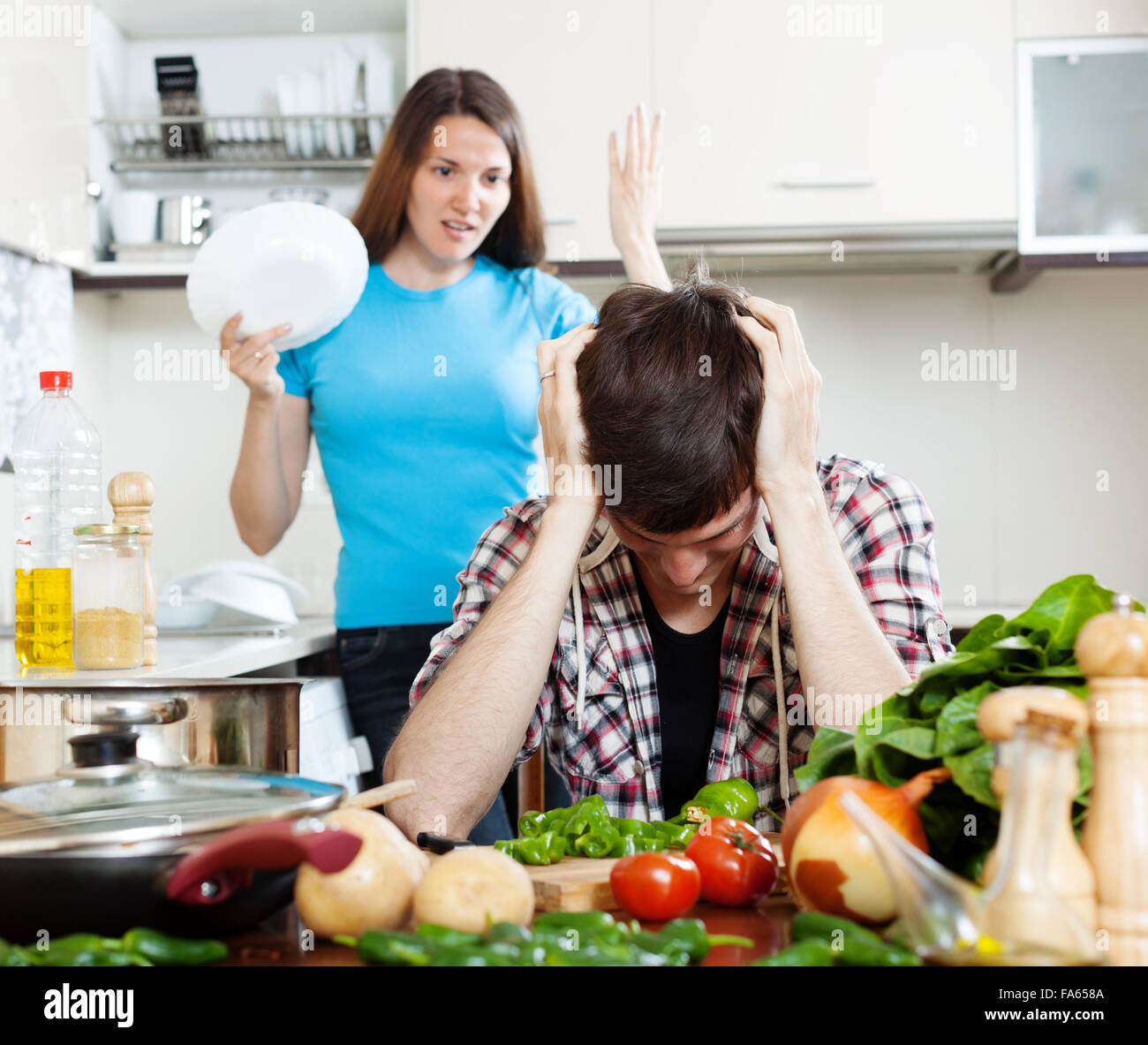 Sad man with angry wife at kitchen. Focus on guy Stock Photo - Alamy