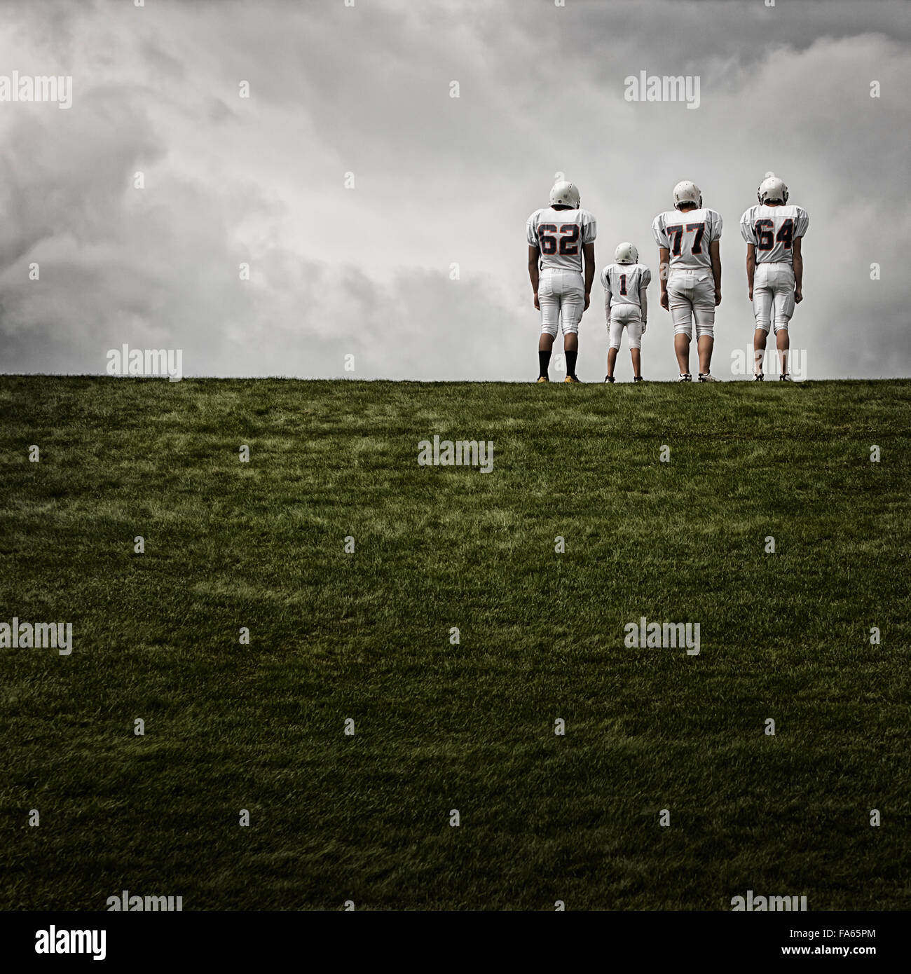 A group of four football players in sports uniform, three tall figures ...