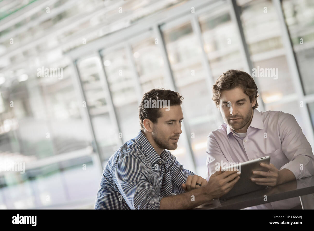 Two men looking at a digital tablet screen Stock Photo - Alamy