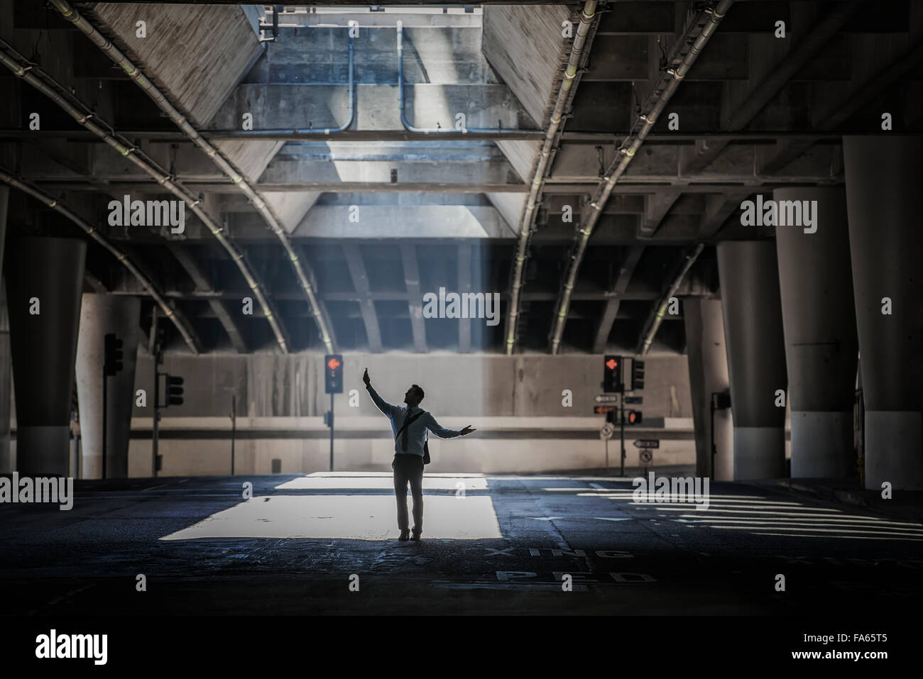 A man in an urban underpass, with concrete and glass structures ...