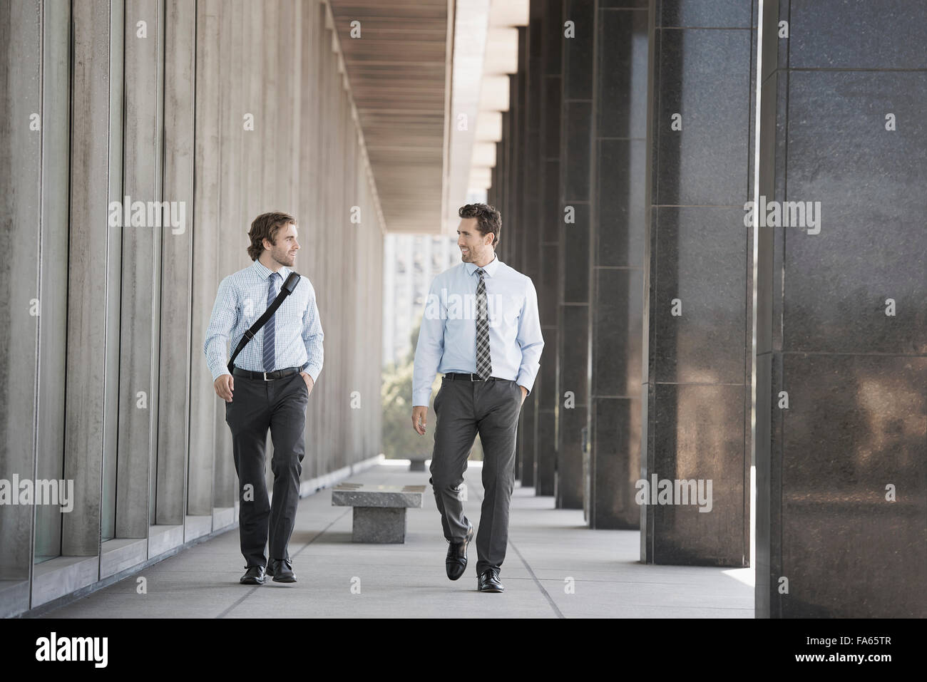 Two businessmen walking along a city street Stock Photo - Alamy