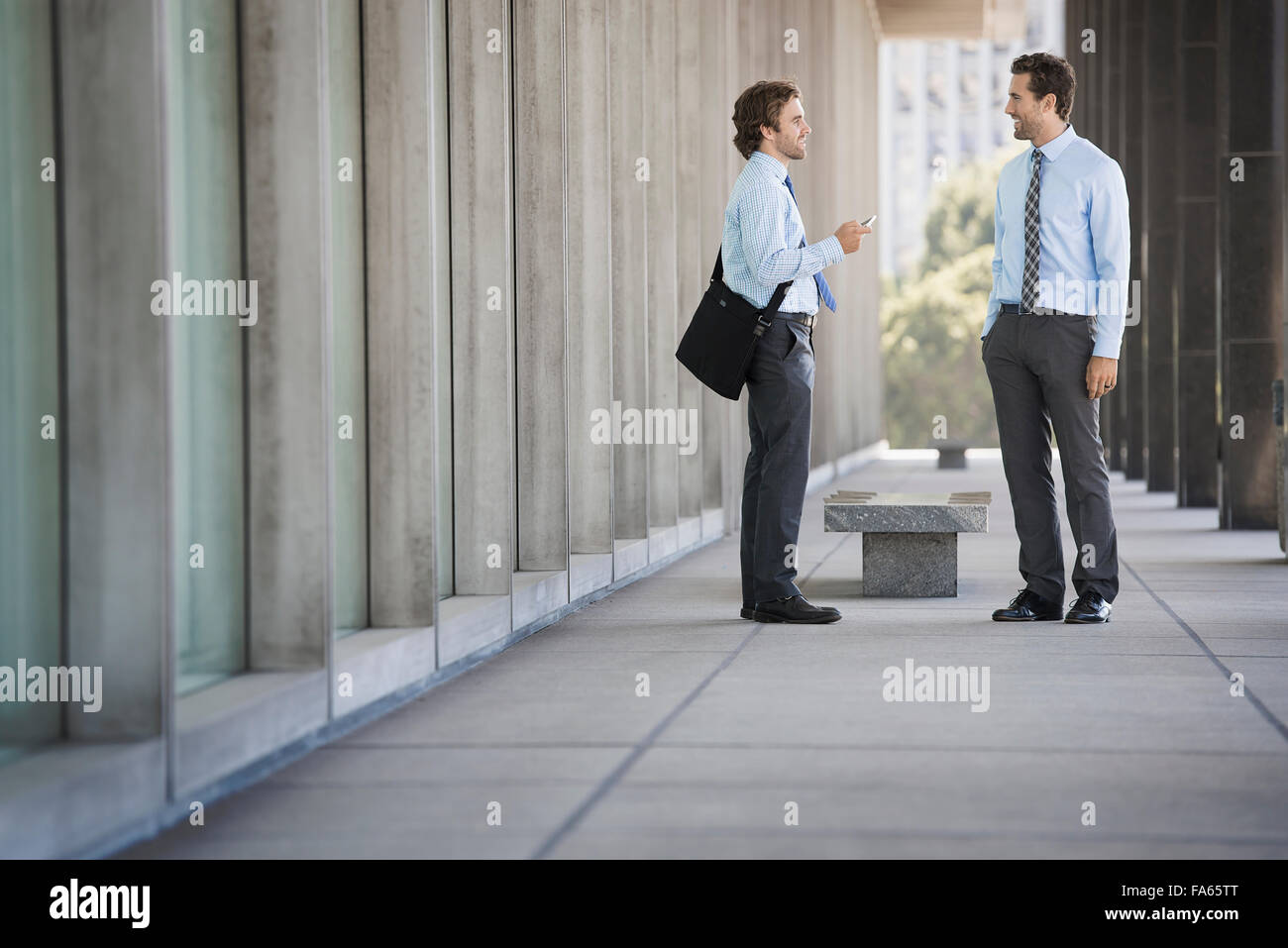 Two businessmen on a walkway outside a building, talking Stock Photo ...
