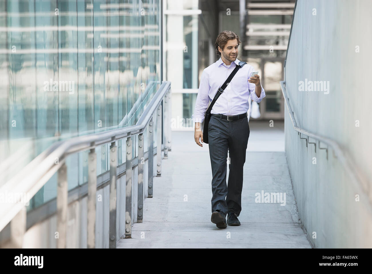 A man carrying a computer bag with a strap across his chest on along a ...